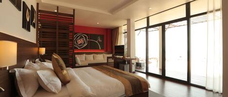 Quarto de hotel moderno com uma cama grande, uma escrivaninha, uma cadeira e vista para o exterior através de grandes janelas.