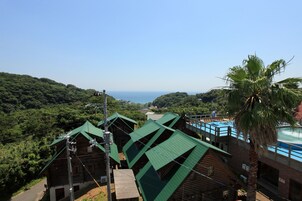 Vista de um resort com várias cabanas, piscina e vista para o oceano.