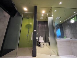 Um banheiro moderno com box de vidro, vaso sanitário e um espelho grande.