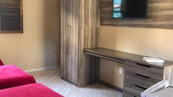 Quarto com cama, escrivaninha, guarda-roupa e televisão.