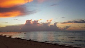 Uma praia com mar calmo e céu ao pôr do sol.