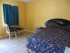 Quarto com cama, uma cadeira, uma mesa pequena e telefone.