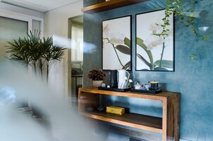Uma sala de estar moderna com uma mesa consola de madeira, uma planta em vaso e obras de arte emolduradas na parede.