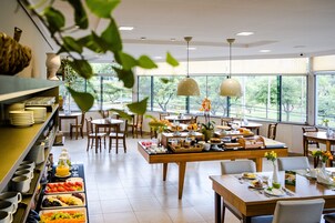 Uma sala de jantar luminosa com buffet, mesas e cadeiras de madeira.