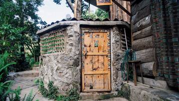 Uma cabana rústica de madeira com uma porta de madeira decorativa e um pequeno banco ao lado.