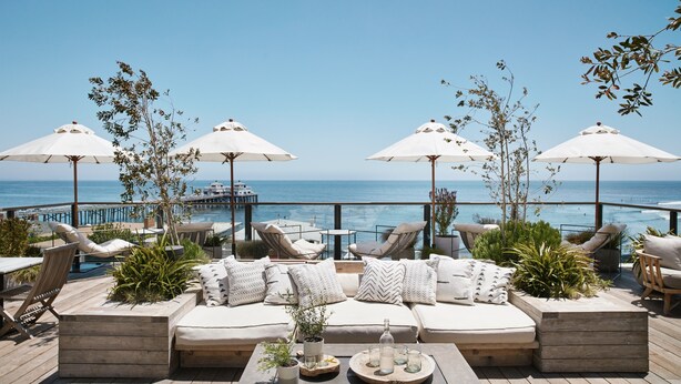 Um terraço com área de estar ao ar livre, guarda-sóis e vista para o oceano.