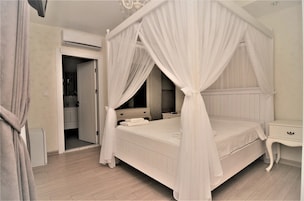 Quarto com cama de dossel, mesa de cabeceira, criado-mudo e guarda-roupa.
