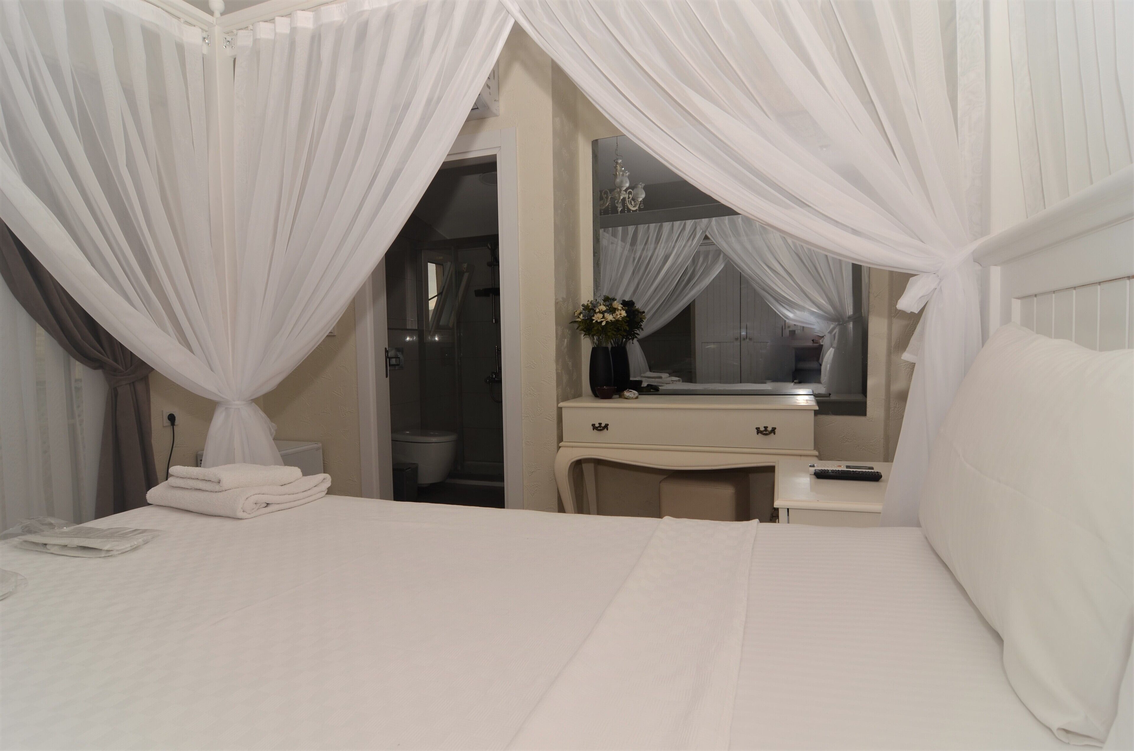 Quarto de hotel com cama, penteadeira com espelho e chuveiro.