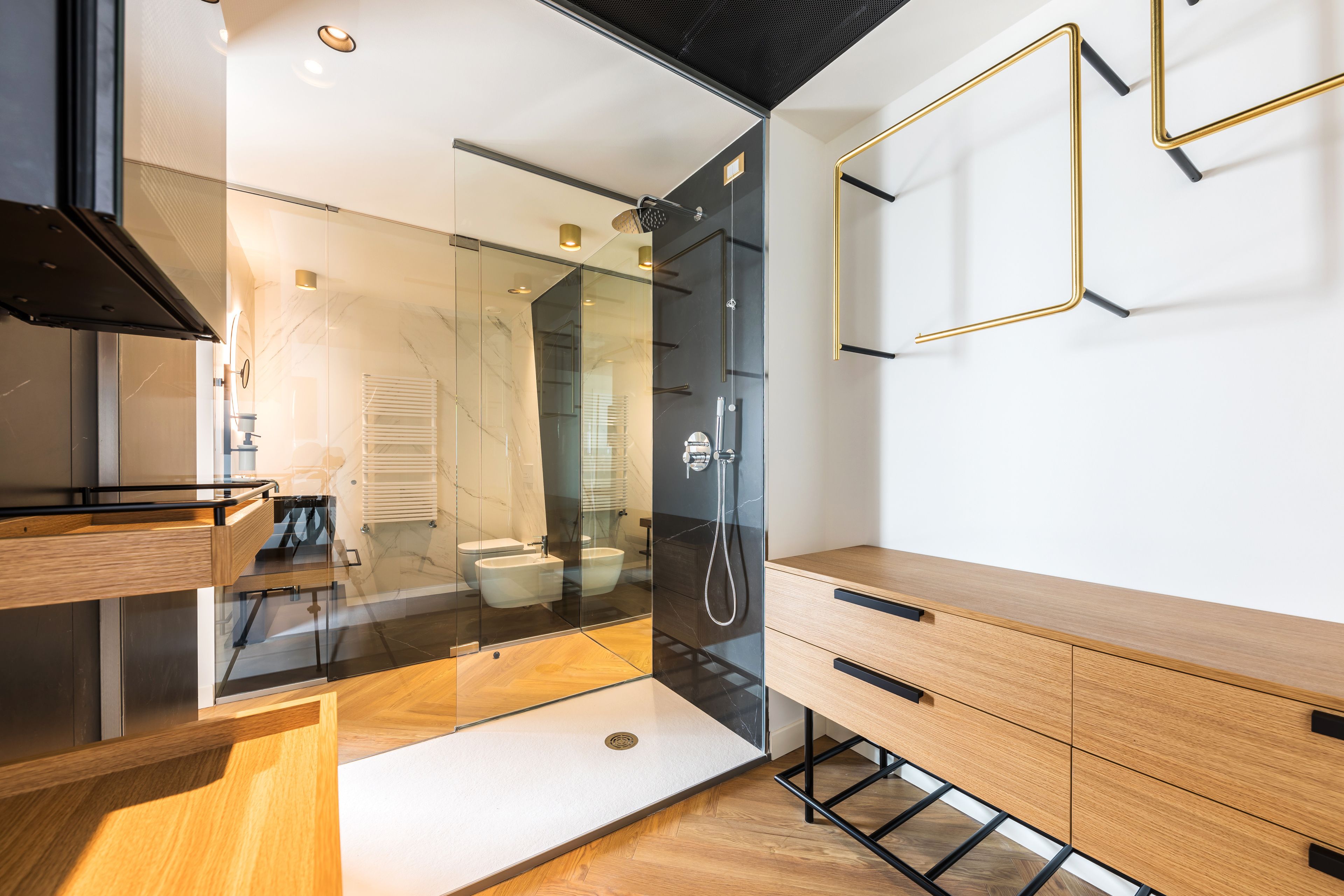 Casa de banho moderna com chuveiro envidraçado, toucador de madeira e design minimalista.