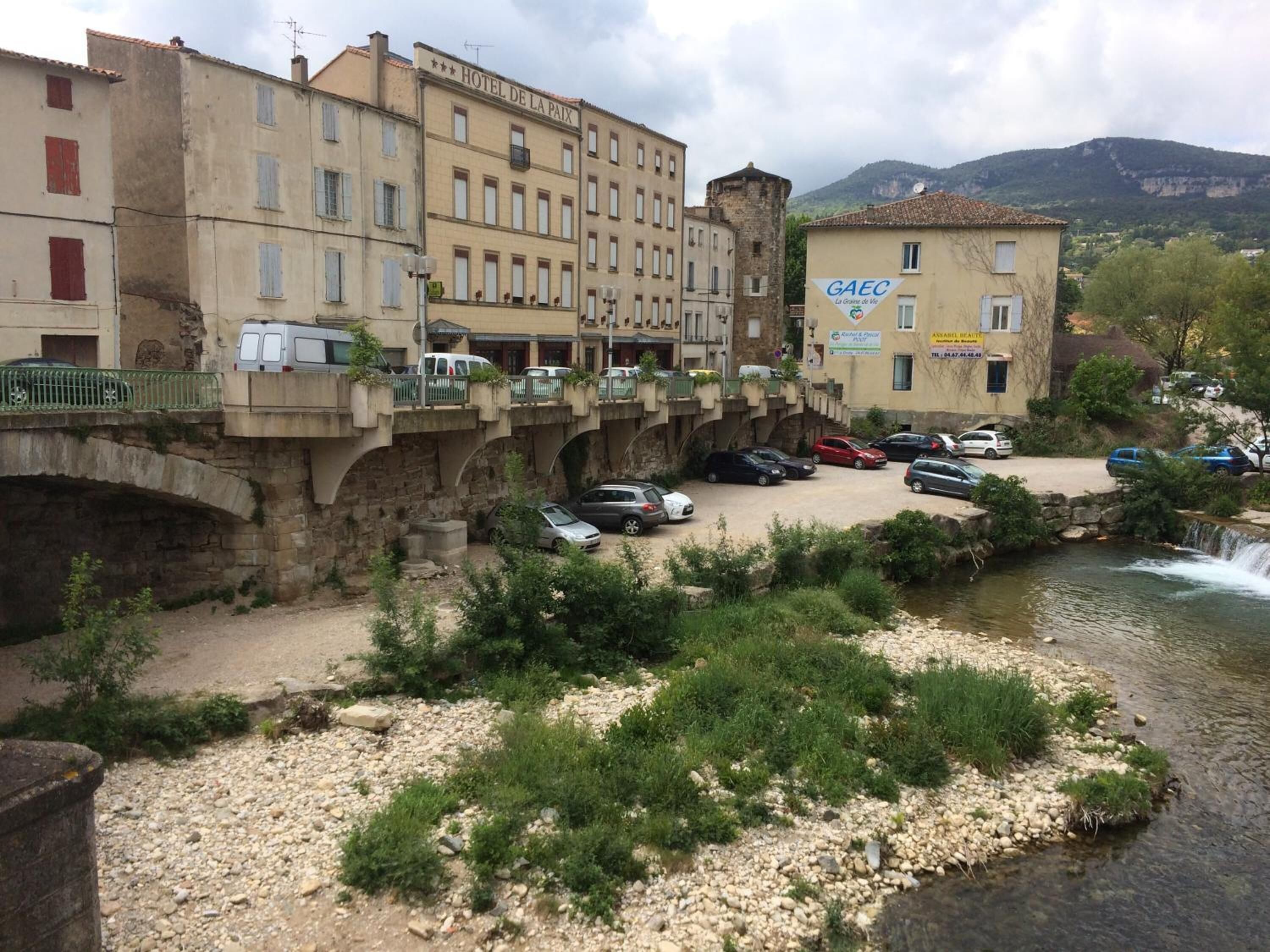 Um hotel com vários andares, uma ponte e uma área de estacionamento com carros.