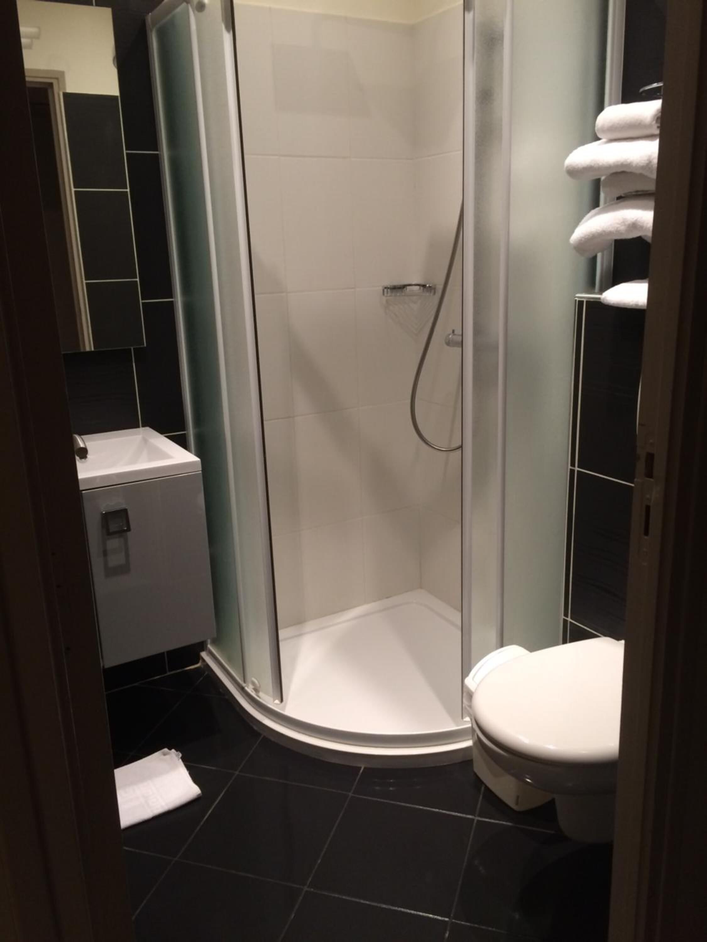 Um banheiro moderno com chuveiro em cabine de vidro, vaso sanitário branco e pia.