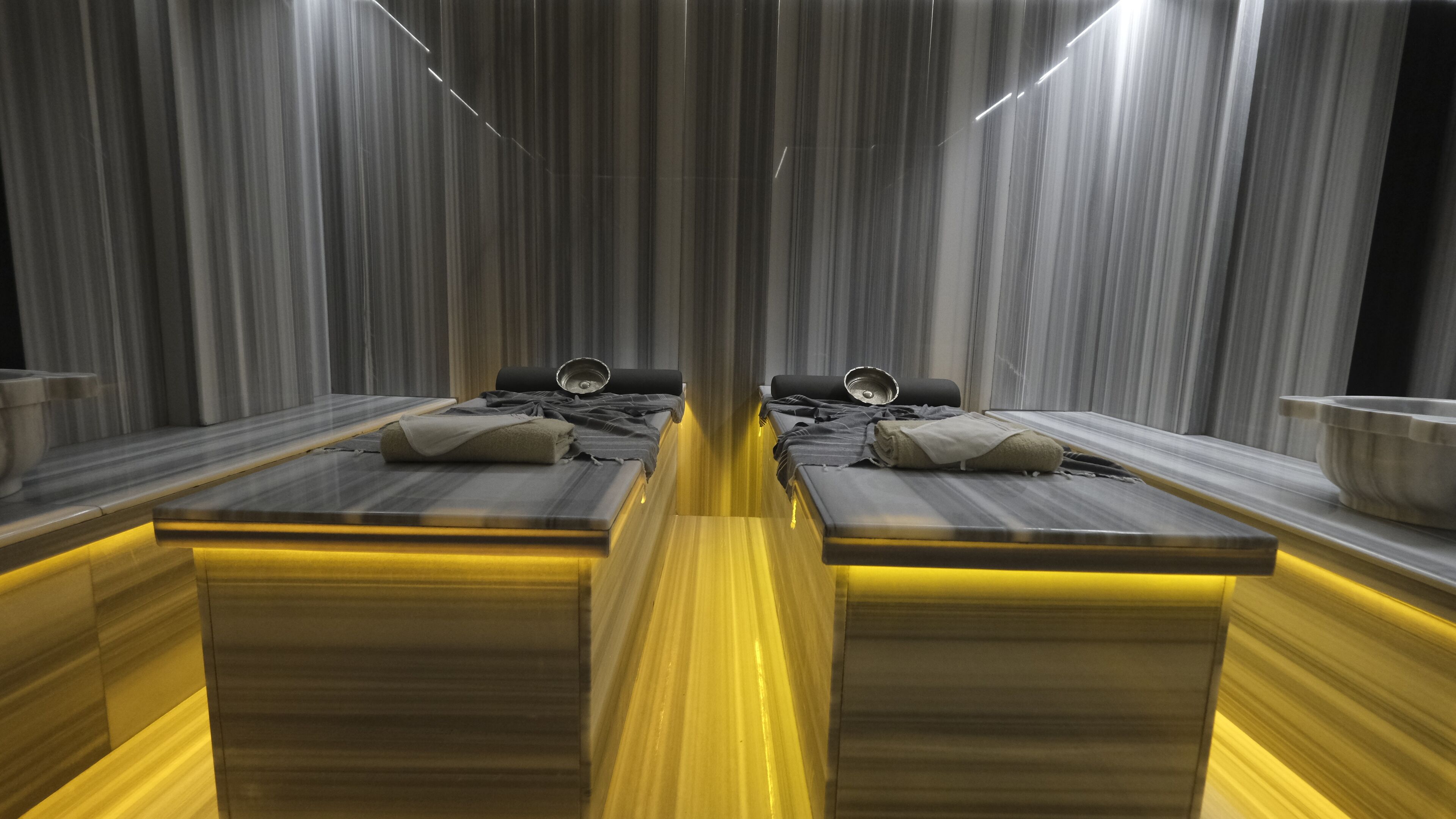 Quarto com espelhos e duas mesas de massagem, cada uma com apoio para a cabeça e uma toalha.