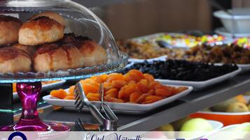 Buffet variado com diversos alimentos, incluindo doces e frutas, e um expositor de vidro.