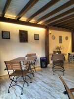 Uma área de refeições com mesas e bancos de madeira, teto com vigas aparentes e arte decorativa nas paredes.