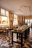 Um restaurante com chão xadrez, mesas e cadeiras de madeira.