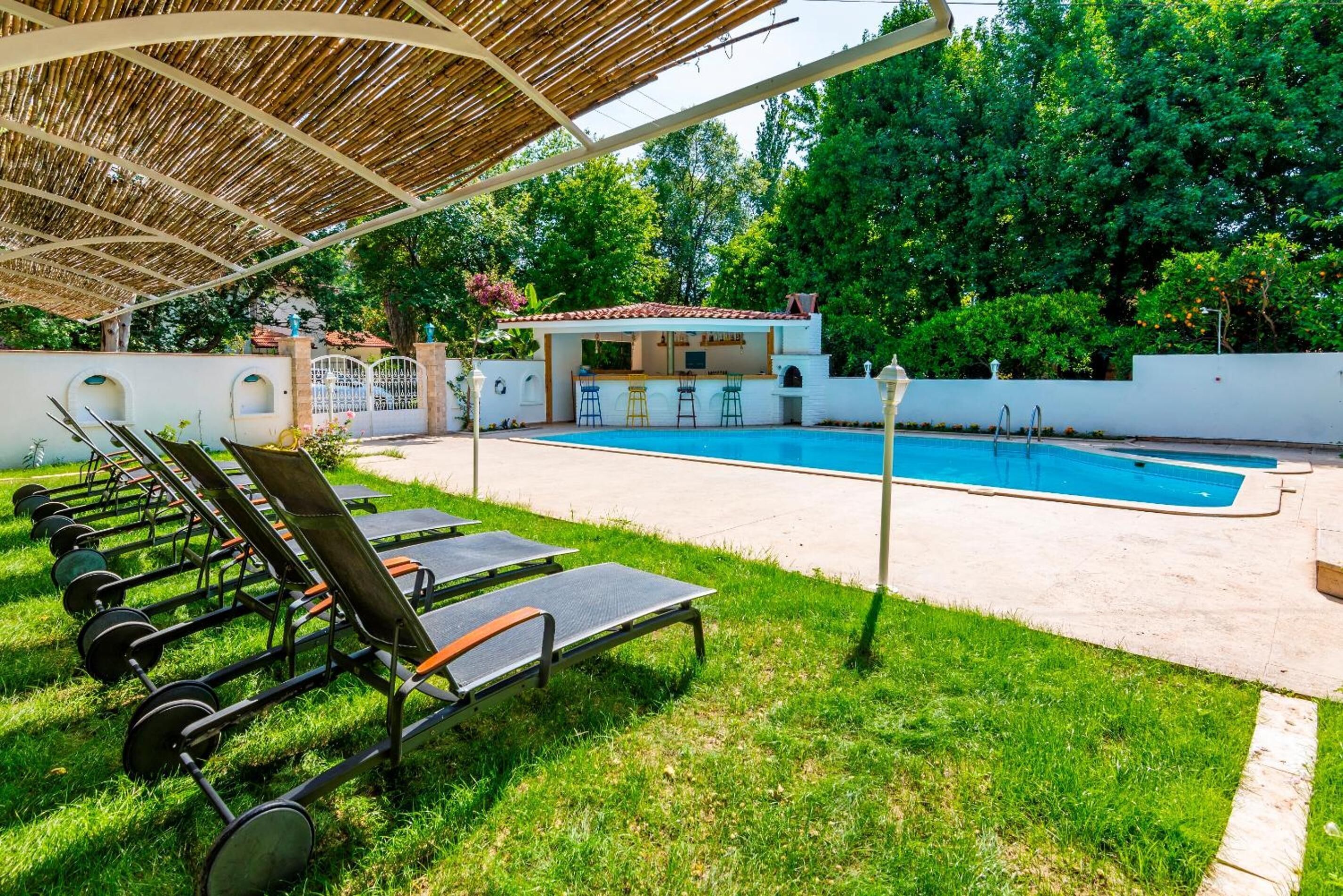 Uma área de piscina com espreguiçadeiras e um espaço de estar coberto.