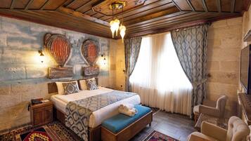 Quarto com uma cama, um banquinho, uma cadeira, uma mesinha, um relógio de parede e um objeto decorativo na parede.