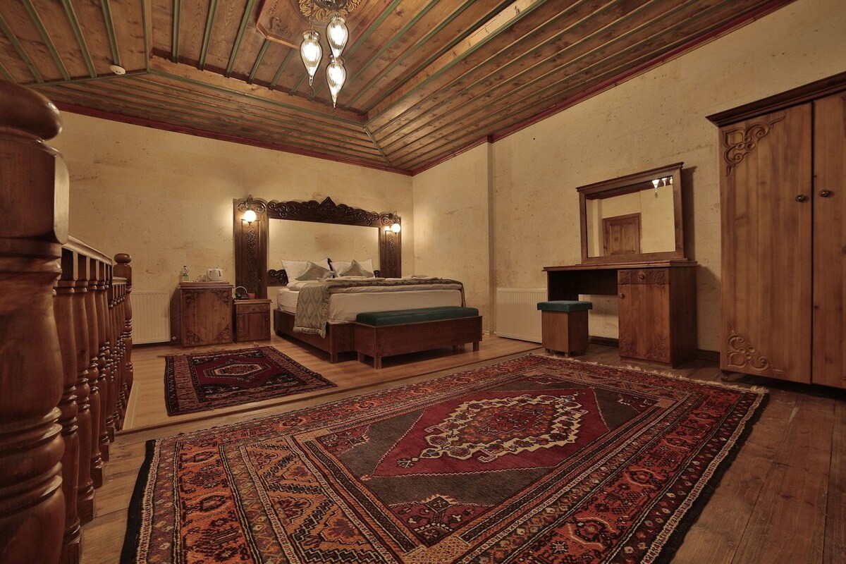 Quarto tradicional com cama de madeira, cômoda, espelho e dois tapetes.