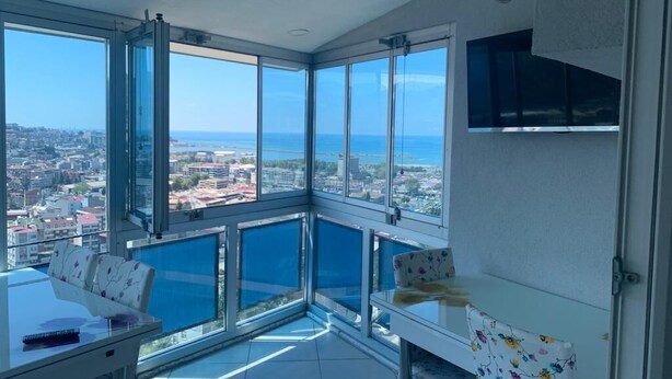 Apartamento alto com grandes janelas, oferecendo vista para a cidade e para o mar.