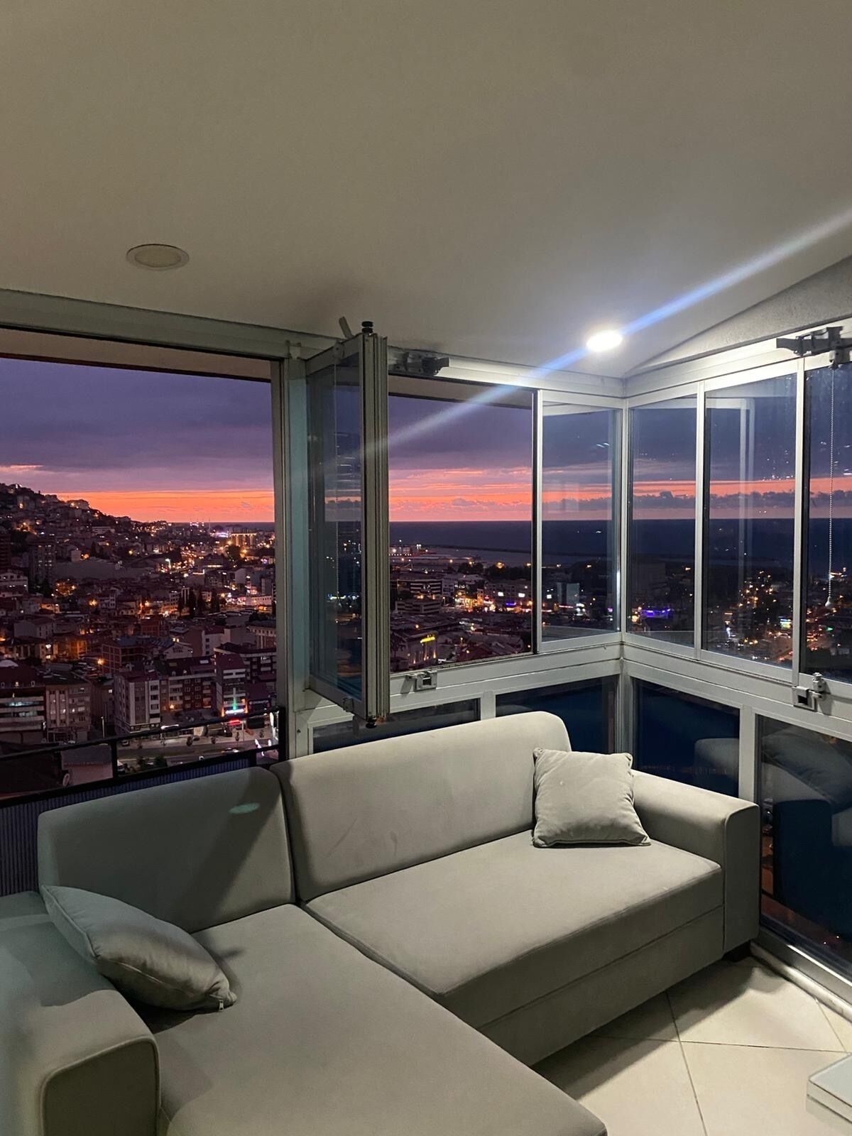 Quarto em um prédio alto com vista para a cidade, um sofá e uma janela grande.