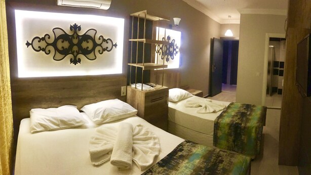 Quarto de hotel com cama, poltrona, mesa de cabeceira e espelho.