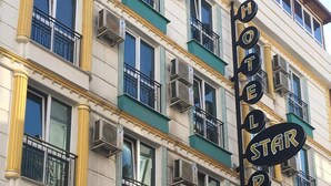 Um hotel com vários andares, varandas, aparelhos de ar condicionado e uma placa chamativa com a inscrição "Star Palace Hotel".