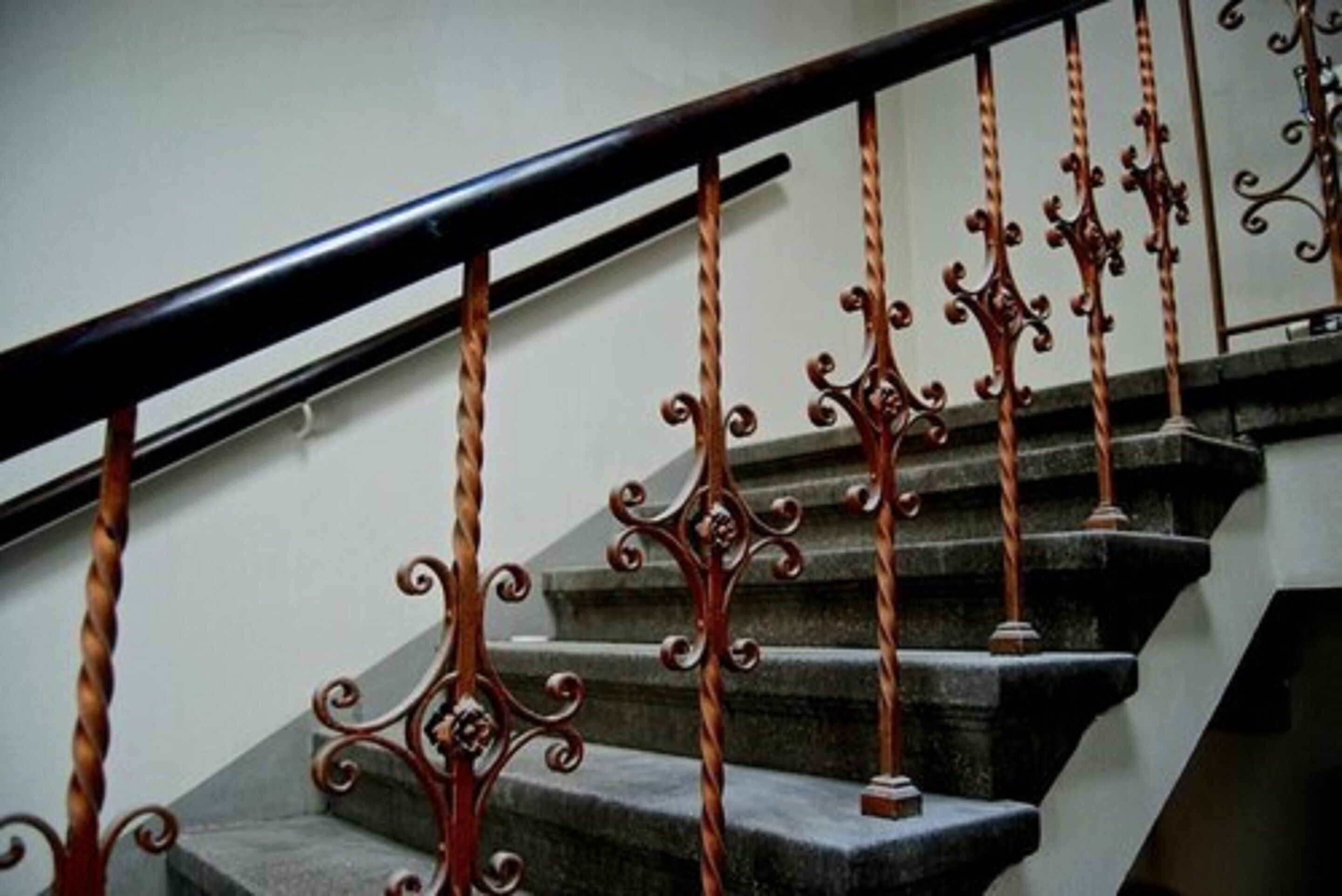 Uma escadaria com grades de metal elaboradas e degraus de pedra.