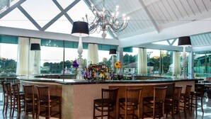 Uma área de bar com teto alto, grandes janelas e um candelabro.