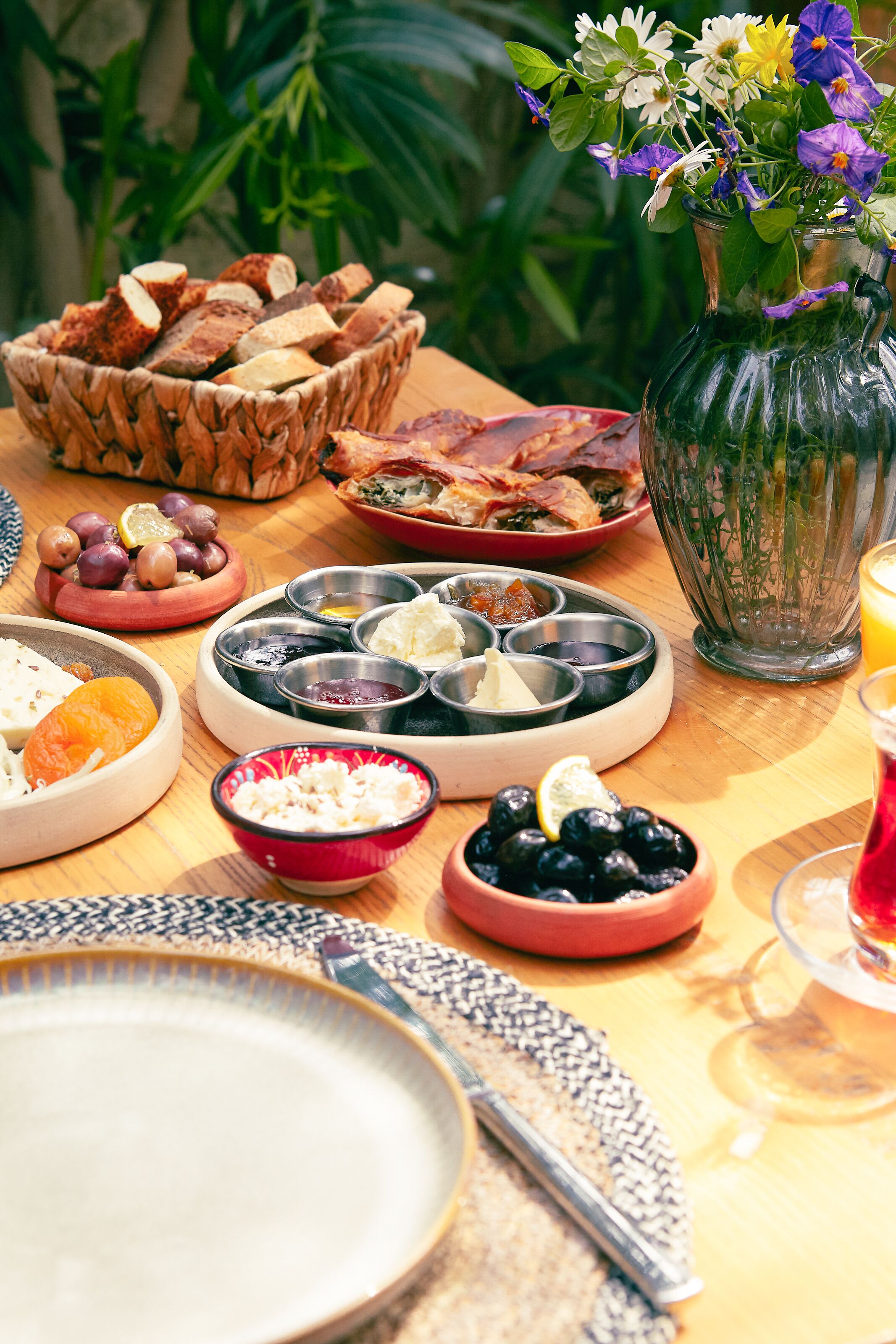 Uma mesa com diversos alimentos e um vaso de flores.