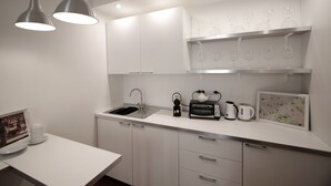 Uma cozinha moderna com armários brancos, uma pia, uma torradeira e um espaço para vinhos.