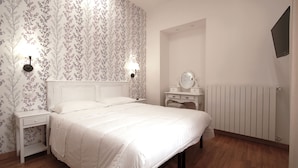 Quarto com cama, mesas de cabeceira, cômoda, espelho e radiador.