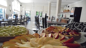 Um buffet com diversas travessas de frutas, incluindo maçãs e uvas.