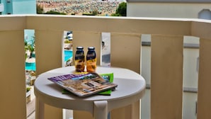 Varanda com vista para a praia e oceano, uma mesa redonda com uma revista e duas garrafas de San Pellegrino, e uma cadeira.