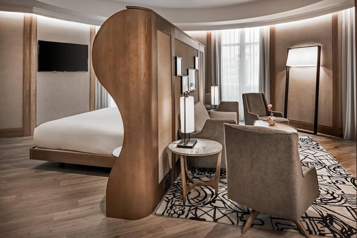 Quarto de hotel moderno com uma cama grande, uma escrivaninha e uma cadeira.