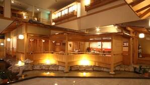 Um interior em estilo japonês tradicional com estrutura de madeira central, caminho de pedra e vários níveis.