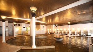 Piscina interior ampla, com várias pistas de natação, rodeada por colunas brancas e iluminada por luzes no teto.