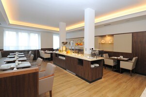 Um restaurante moderno com uma ilha central, várias áreas de estar e piso de madeira.