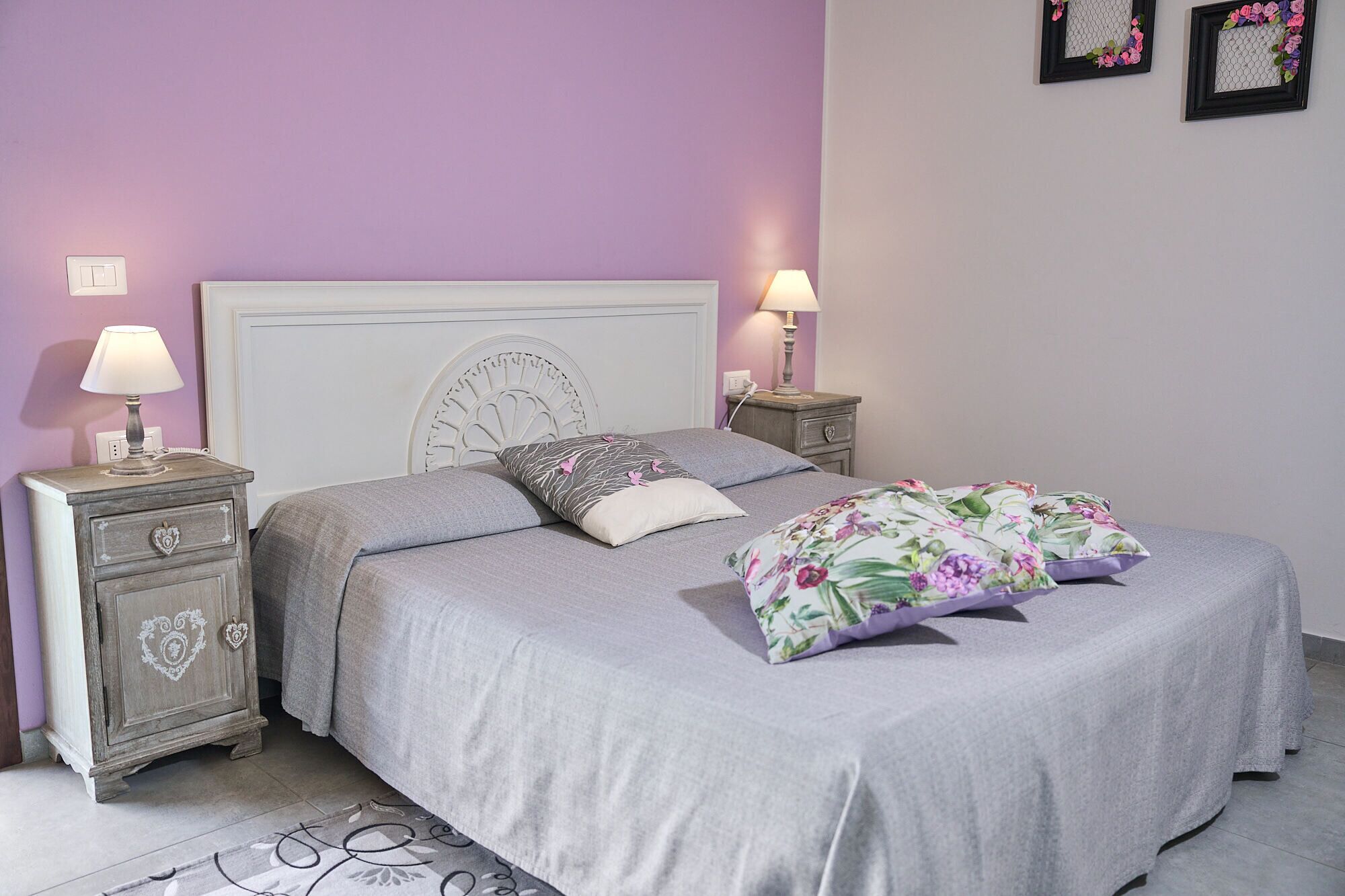Quarto com cama, duas mesas de cabeceira e colcha estampada.