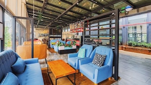 Decoração moderna com sofás azuis, mesas de madeira e um espaço de bar com prateleiras.