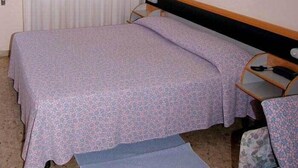 Um quarto pequeno e simples com uma cama, uma cadeira e uma mesa.