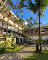 Pátio de hotel com palmeiras, assentos externos e área coberta.