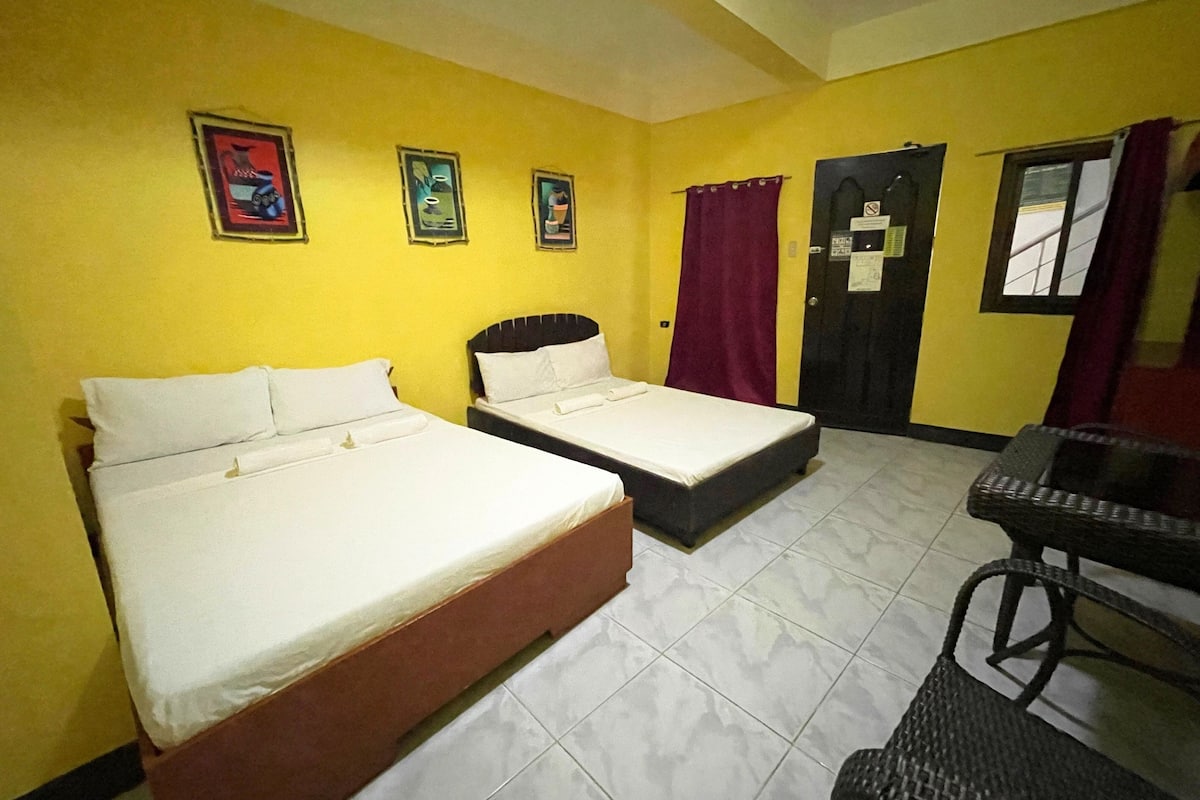 Quarto com duas camas, uma escrivaninha e uma cadeira.