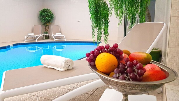 Uma área na piscina com espreguiçadeiras, uma toalha e uma cesta de frutas.