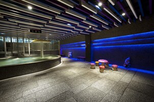 Um interior moderno com balcão de recepção, área de estar e iluminação azul ambiente.