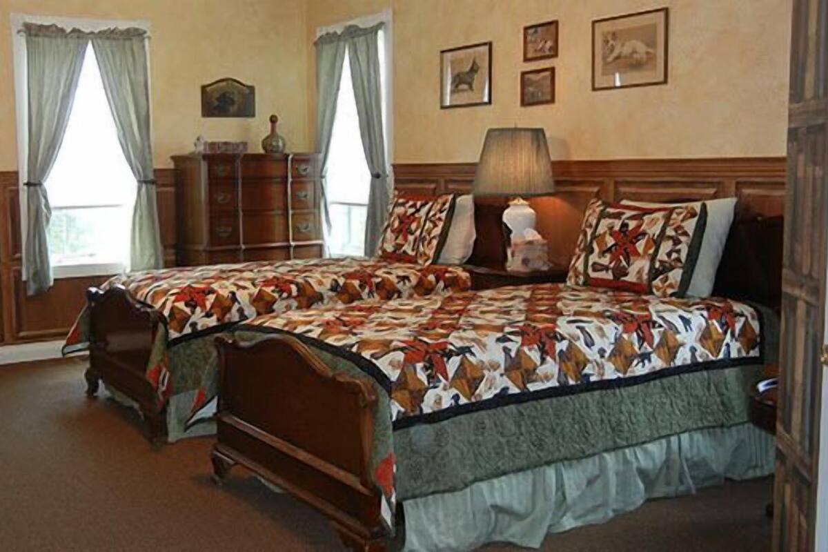 Quarto com uma cama grande, cômoda, mesa de cabeceira e abajur.