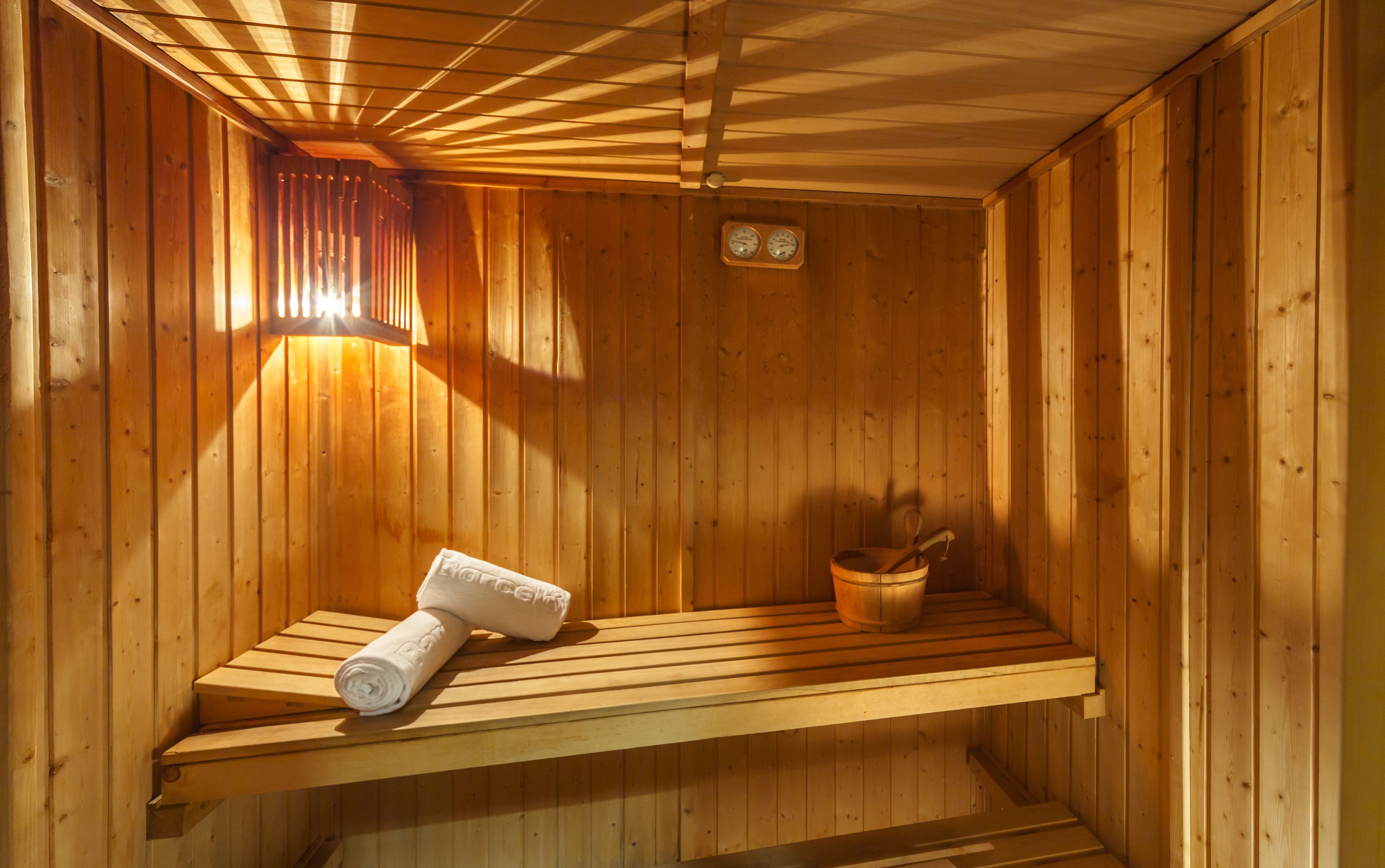 Uma sauna de madeira com bancos, uma toalha e um balde de madeira.