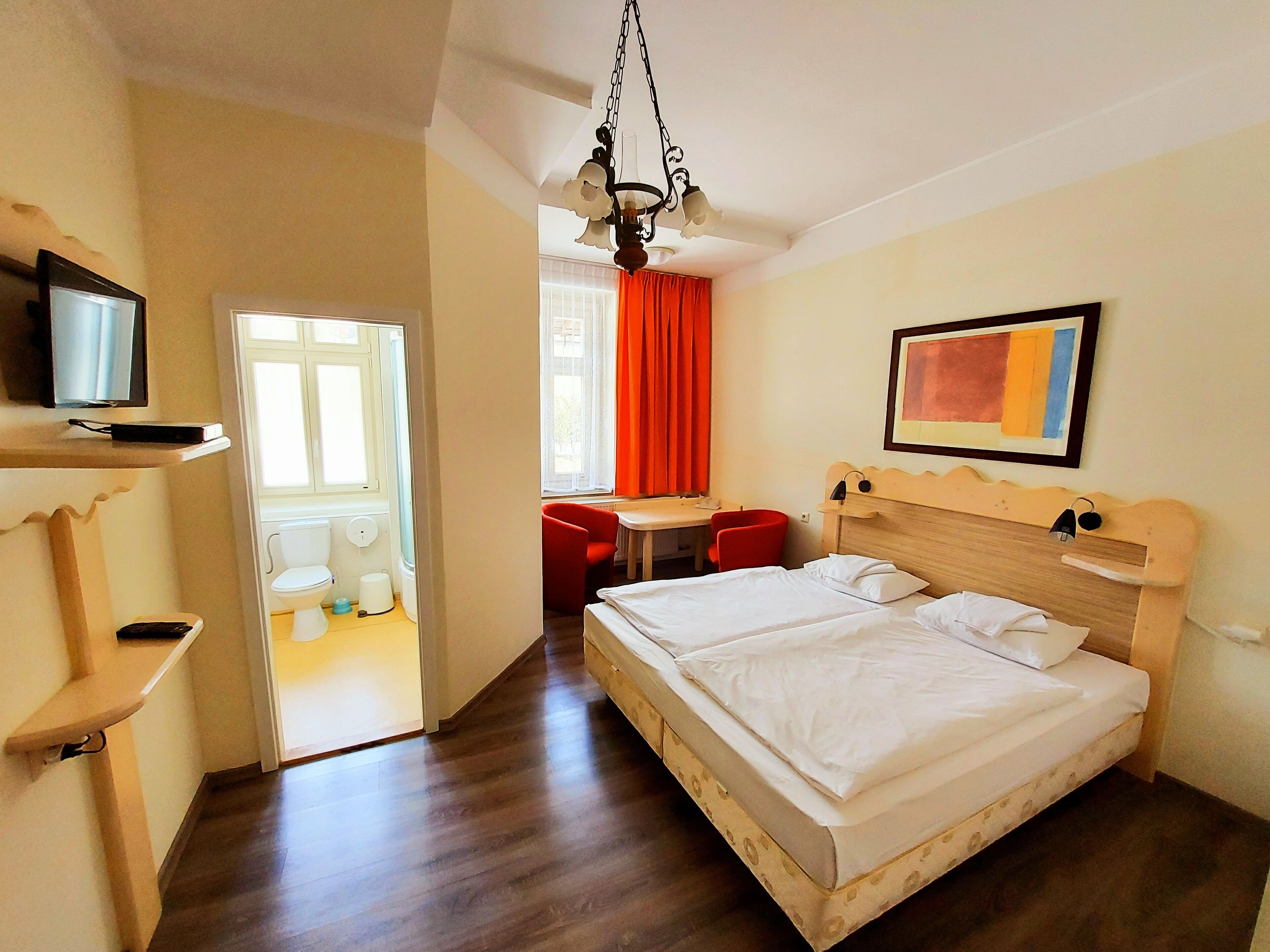 Quarto de hotel com cama, televisão, escrivaninha e cadeira.