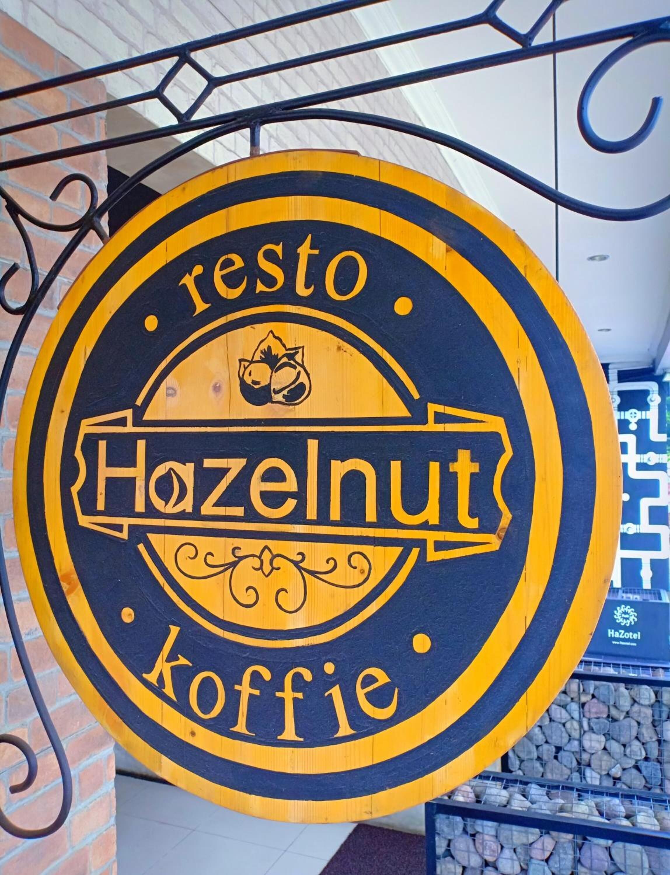 Sinal redondo com as palavras 'resto', 'Hazelnut' e 'koffie', indicando um restaurante.