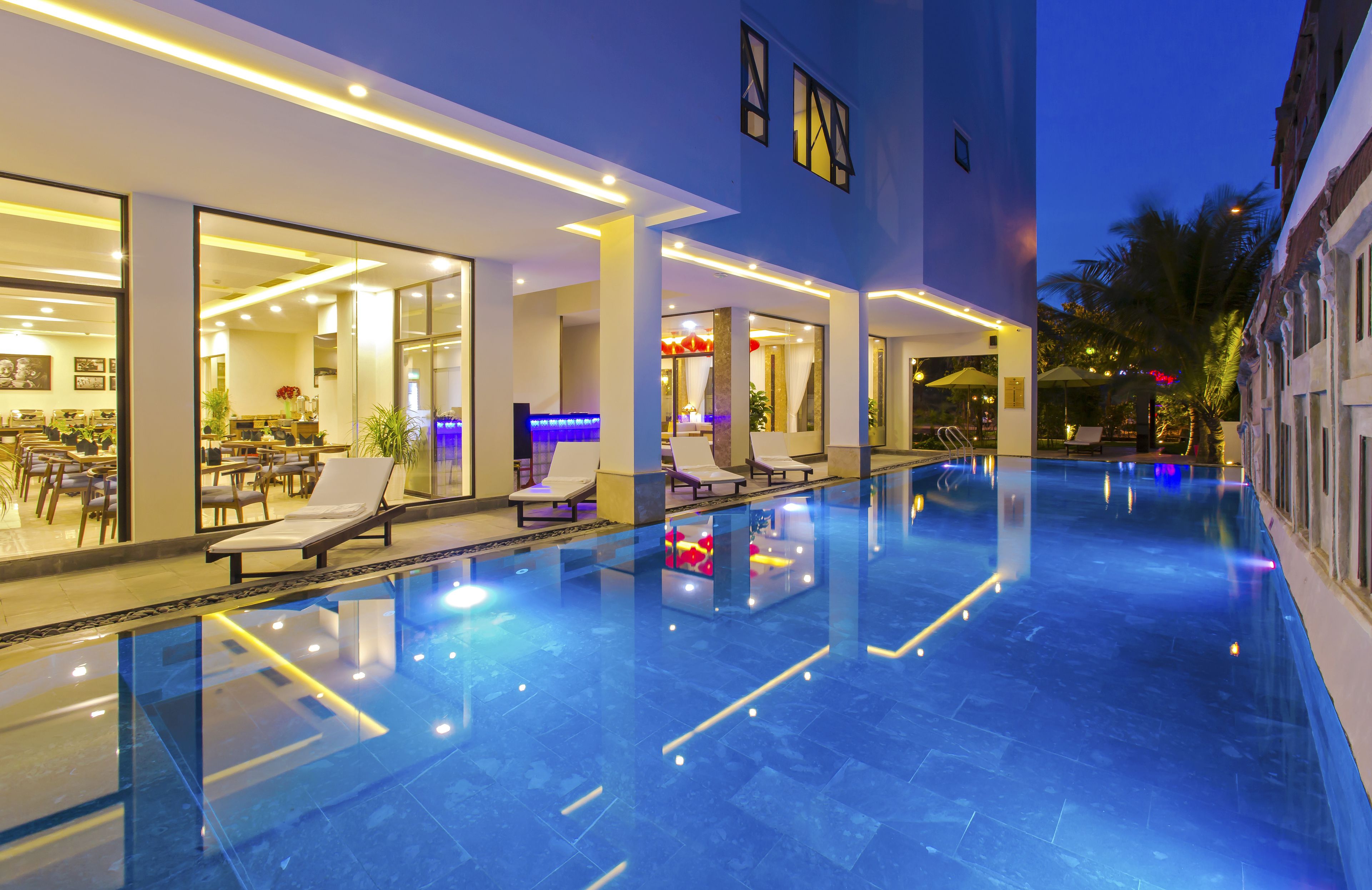 Um hotel moderno com piscina, espreguiçadeiras e interior bem iluminado.