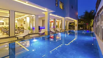 Um hotel moderno com piscina, espreguiçadeiras e interior bem iluminado.
